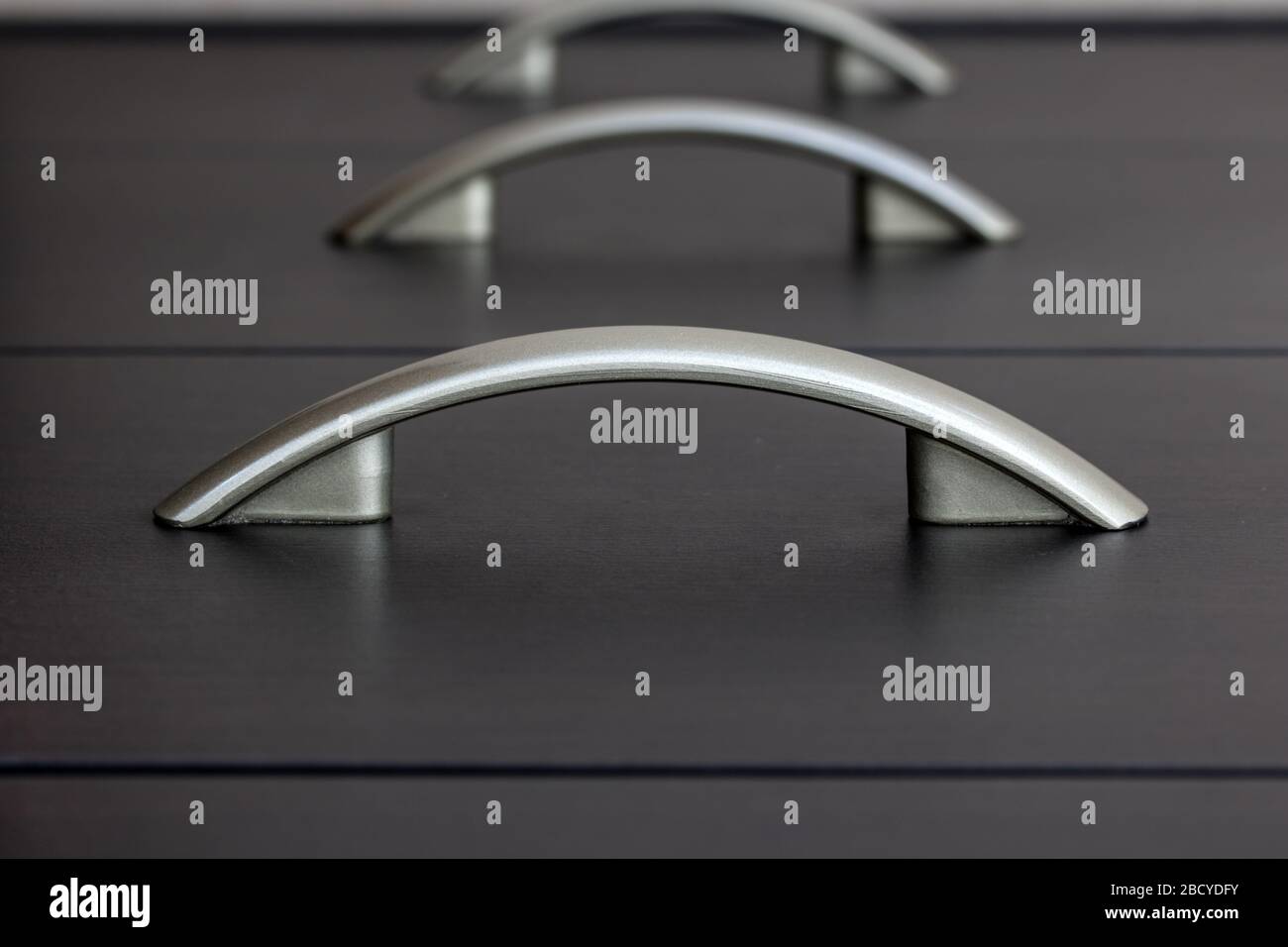 Close-up top view of drawers. Row of black drawers with arched handles ...