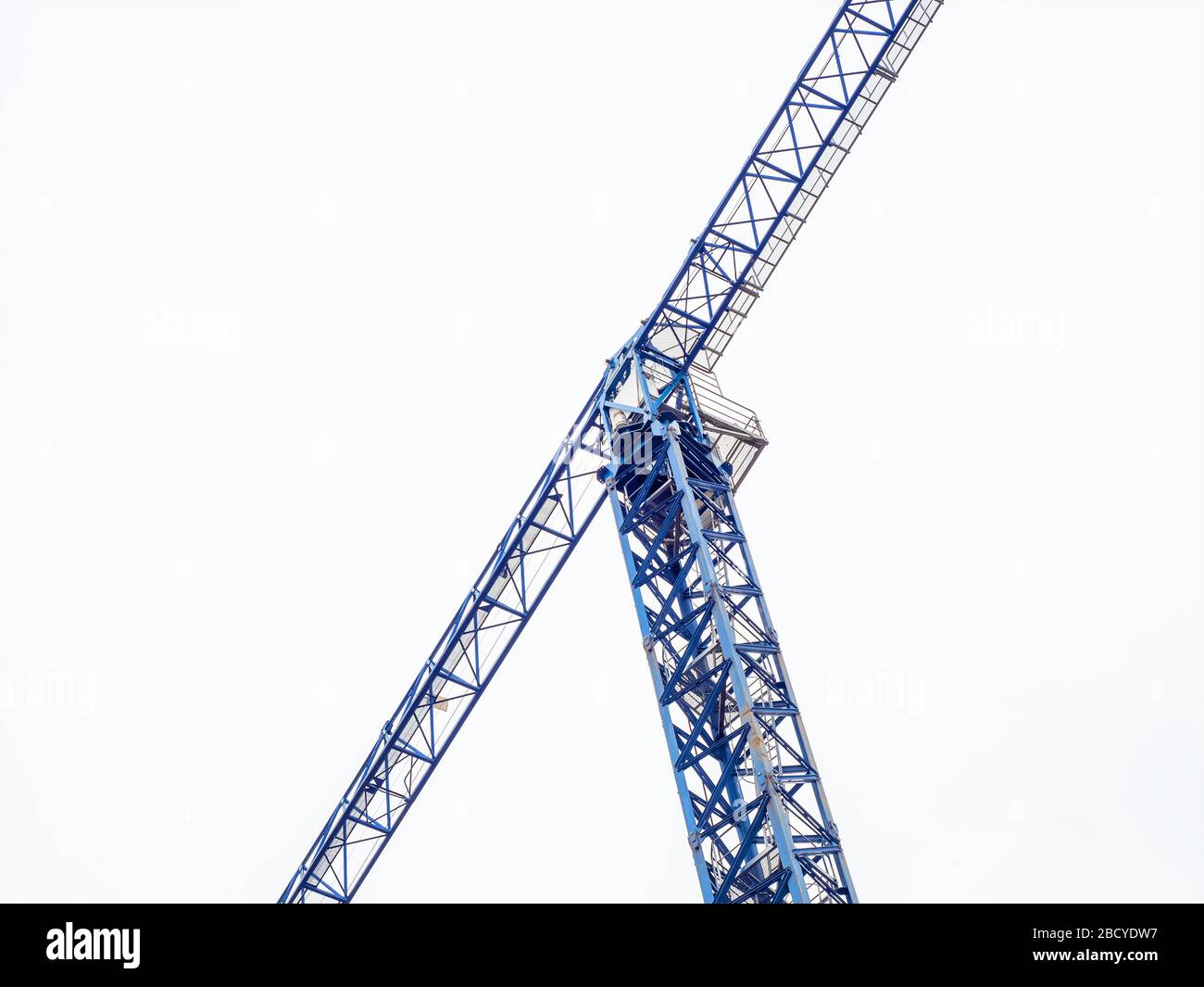 Tall blue tower crane for building houses on a cloudy sky background ...