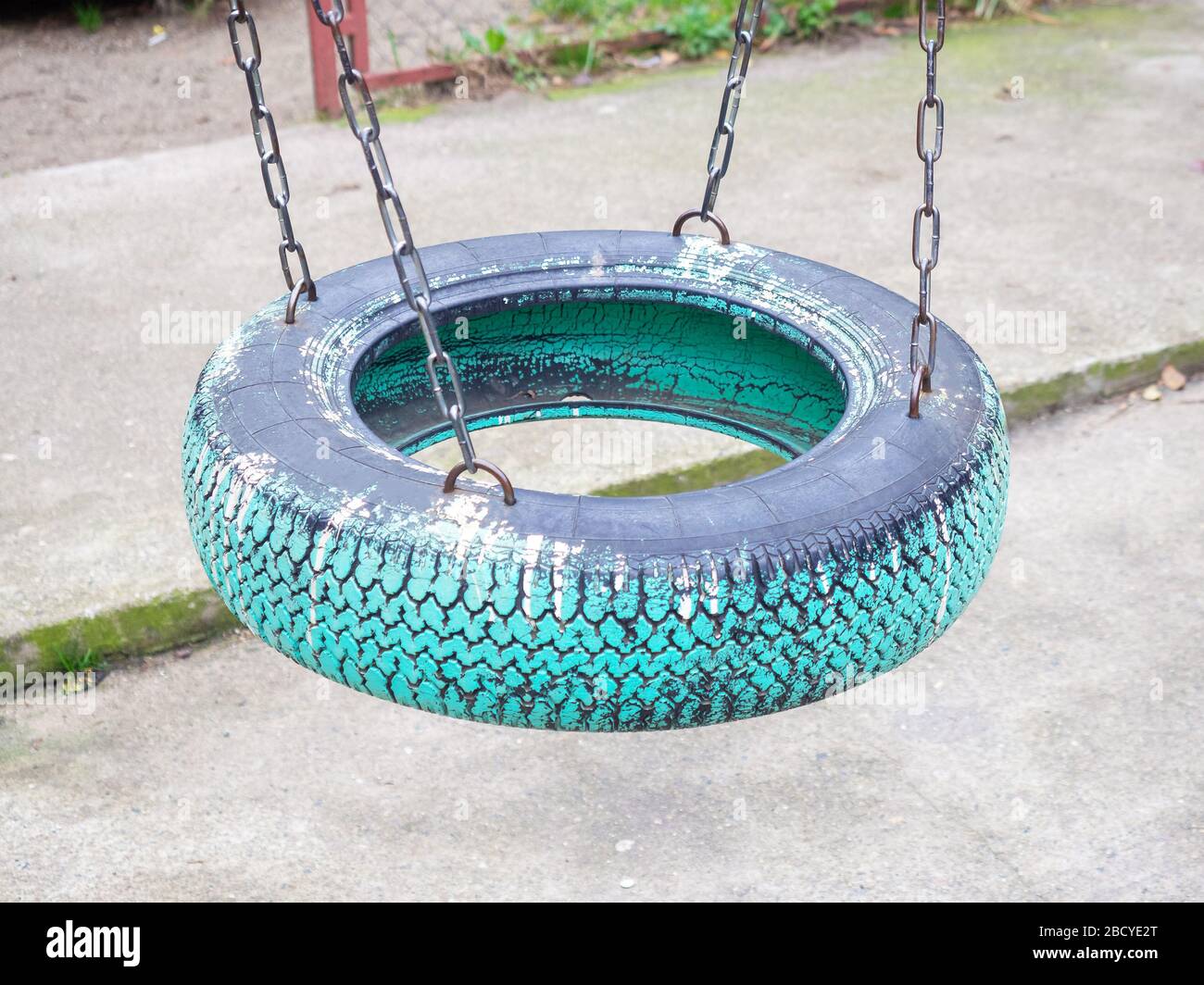 Swing with a seat from a car wheel painted with blue paint and hanging ...