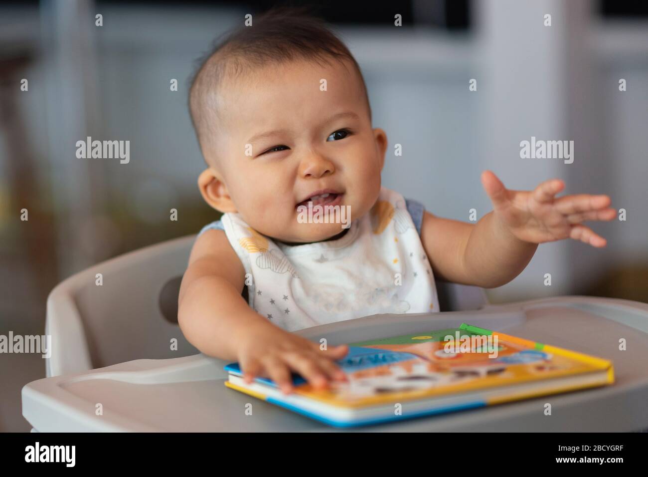 Asian pretty lovely baby girl with her colorul reading book and smile ...
