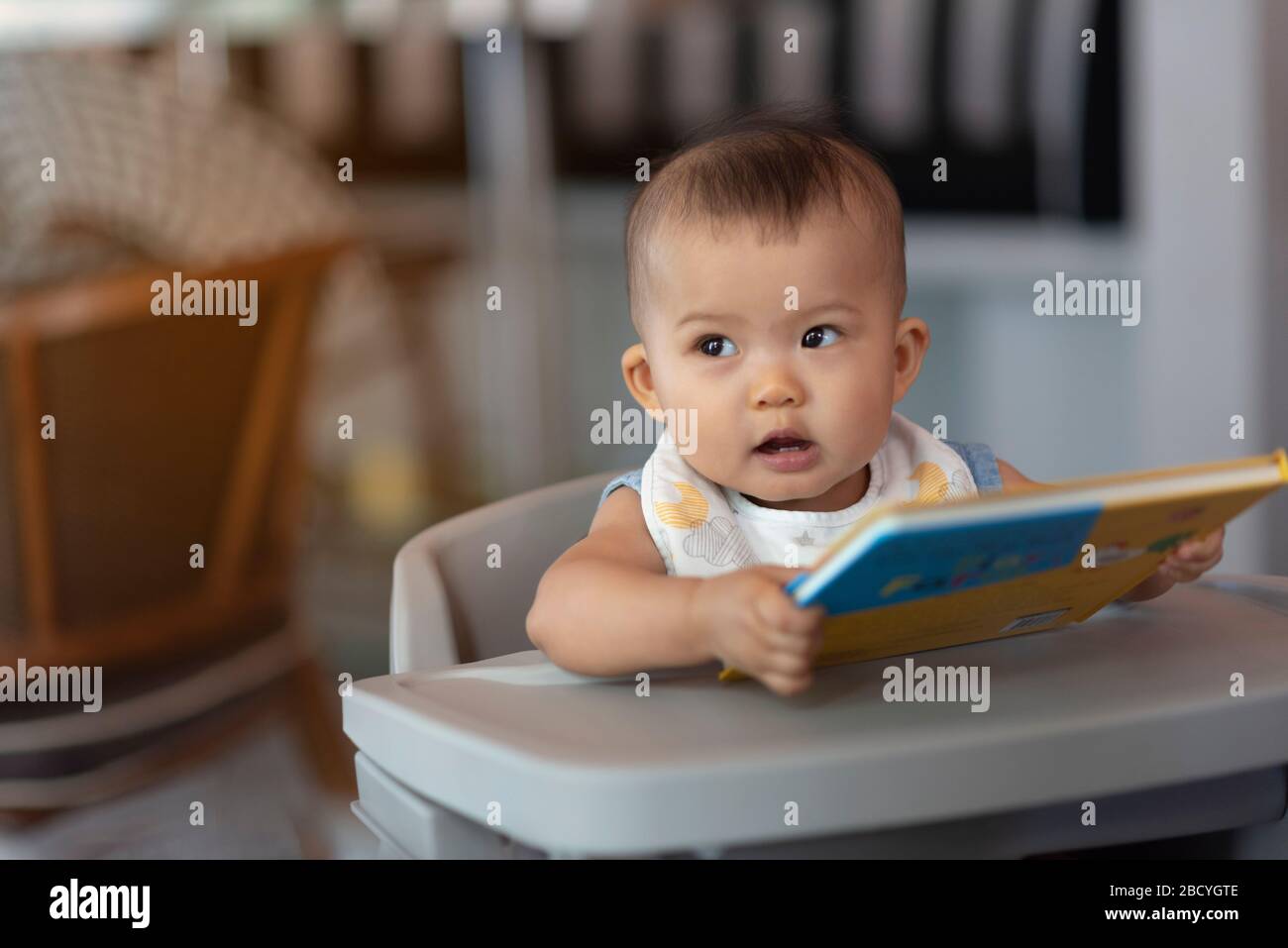 Asian pretty lovely baby girl with her colorul reading book and smile ...