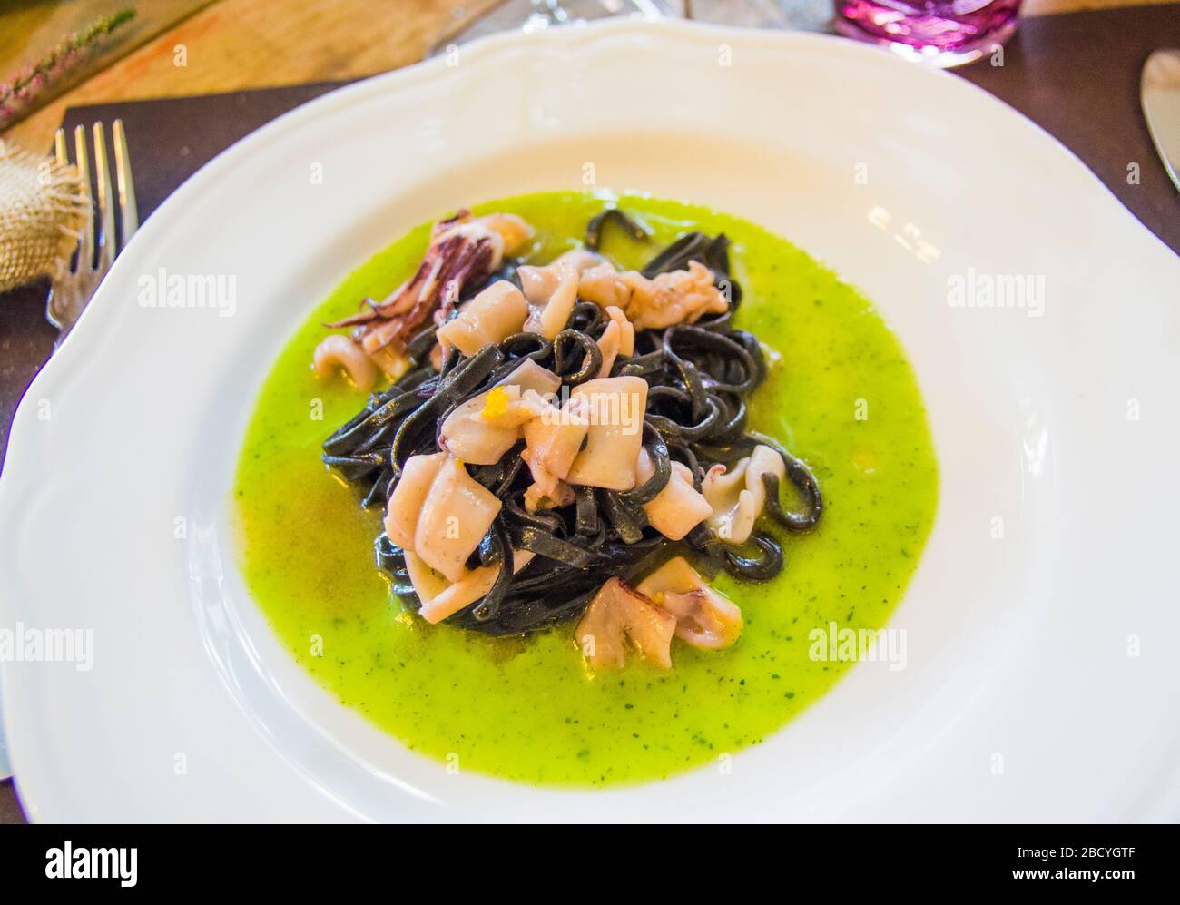 squid ink spaghetti with octopus and squid sauce on a bed of spinach ...