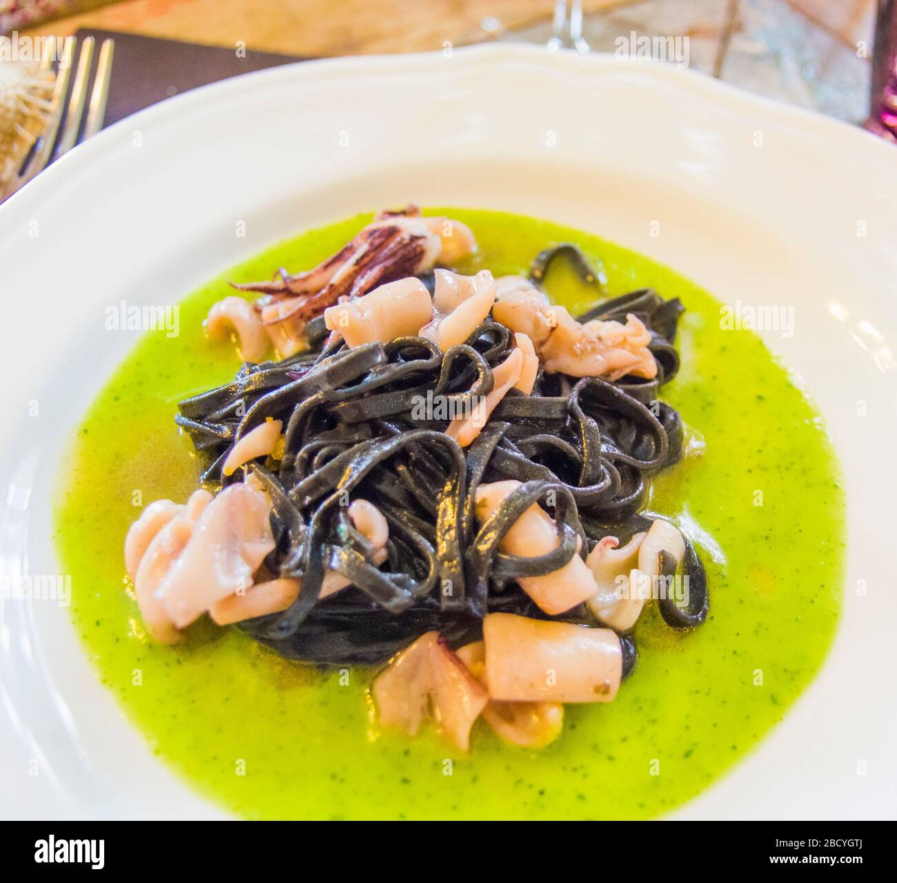 squid ink spaghetti with octopus and squid sauce on a bed of spinach ...