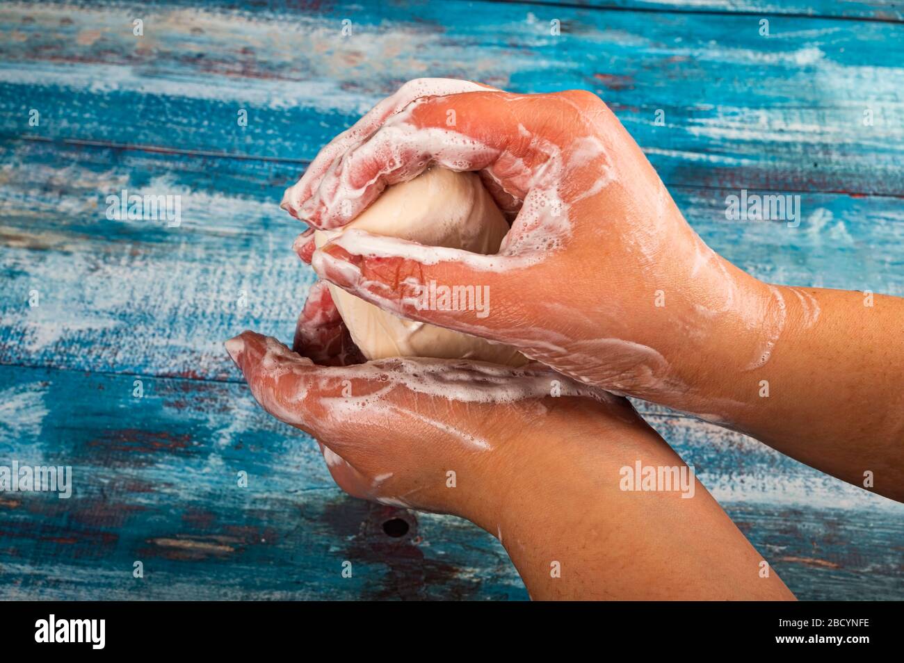 Someone is soaping their hands with a piece of toilet soap on a wooden ...