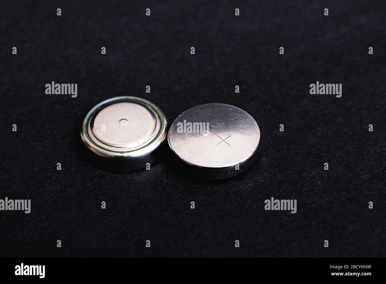 Two round batteries on a black background close up Stock Photo - Alamy