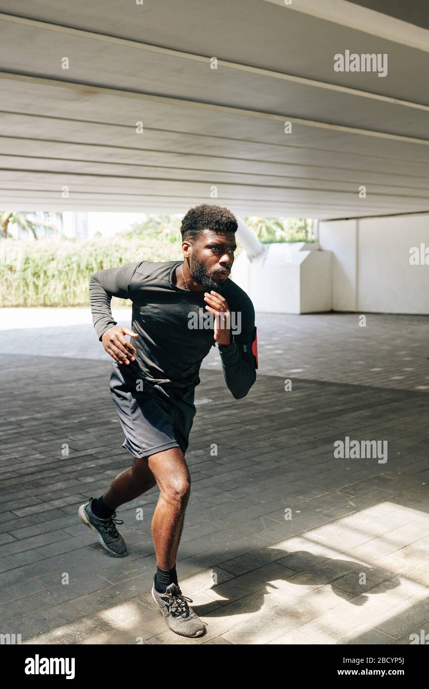 Fit strong African-American sportsman training and jogging outdoors ...