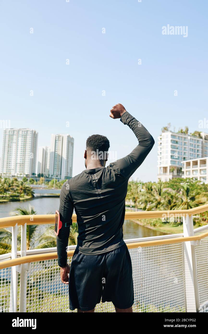 Sportsman looking at city and raising arm to show his excitement after ...