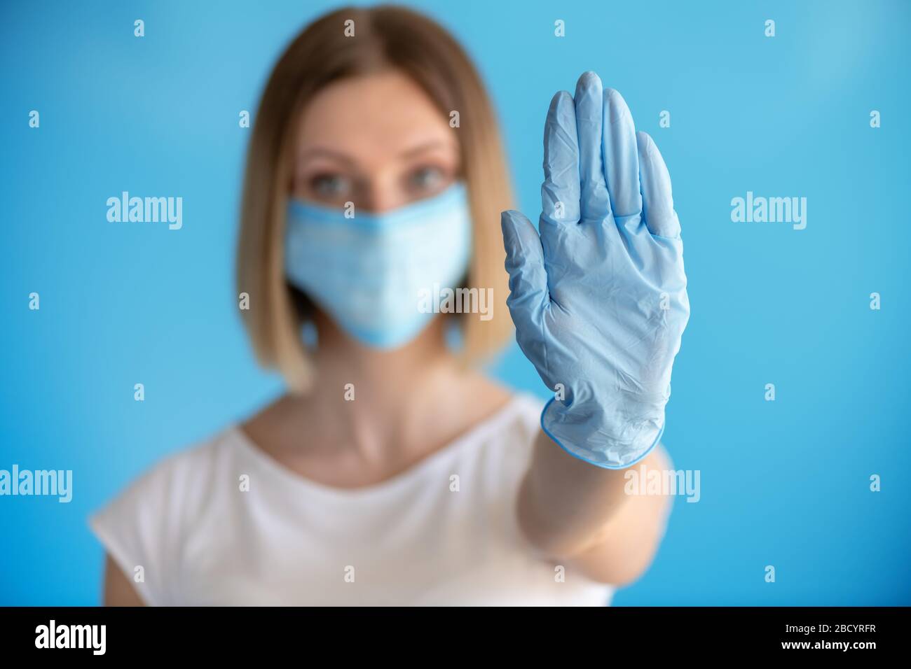 Attractive female nurse showing stop sign with his hand in glove ...