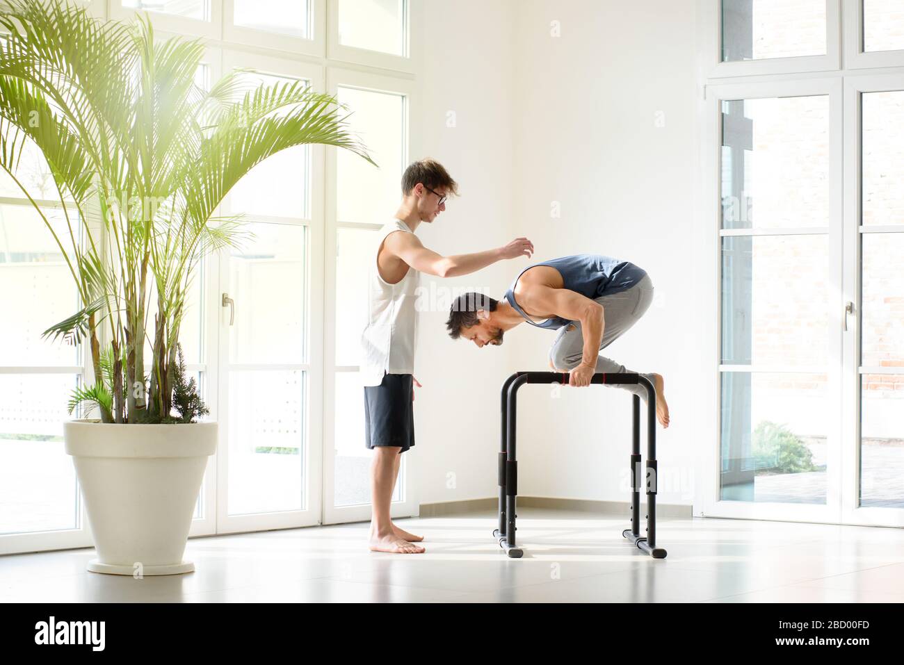 Two men working out doing calisthenics workout with one man assisting ...