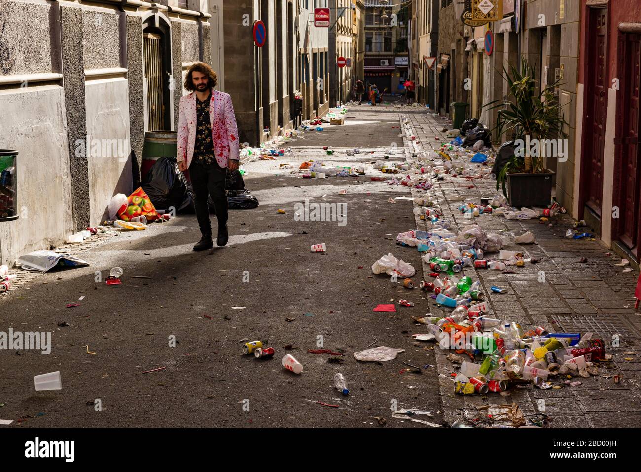 A dressed up man walking through an empty alley full of garbage on the ...