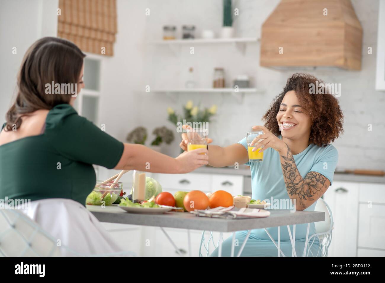 Woman giving a glass of juice to her girlfriend Stock Photo - Alamy