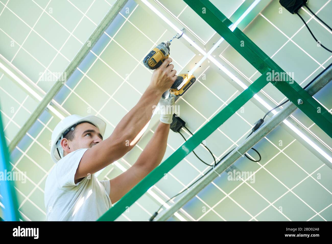 Worker using drill by solar panels installing. Innovative high-tech ...