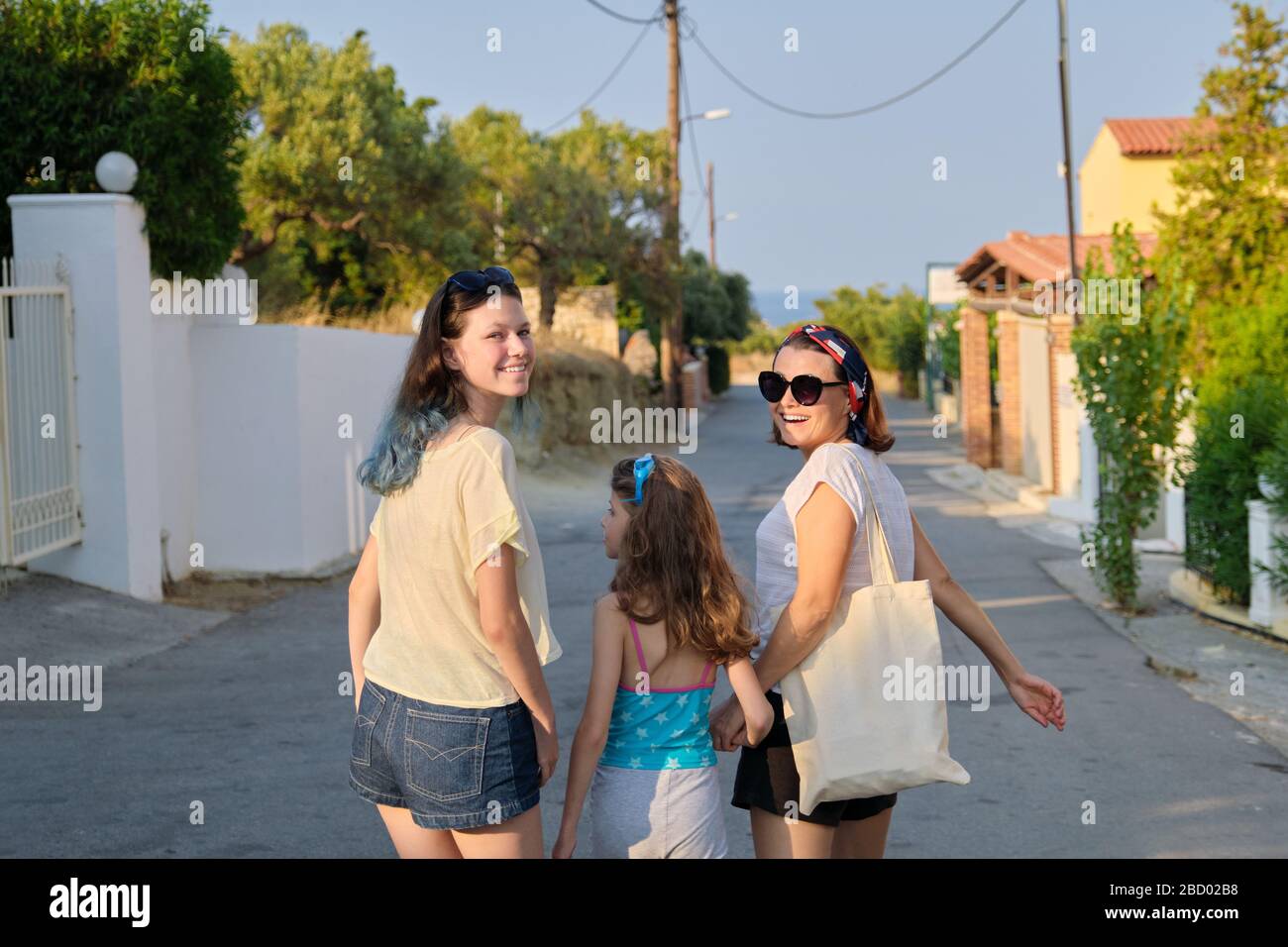 Mother and two daughters teenager and youngest walking together holding hands Stock Photo - Alamy