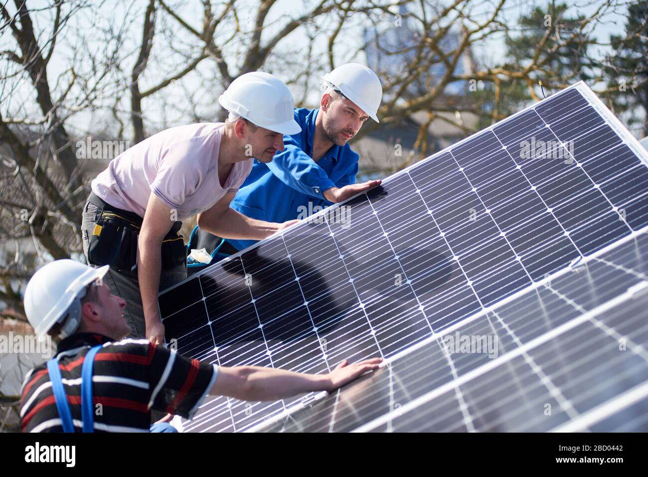 Male team workers installing solar photovoltaic panel system. Three ...