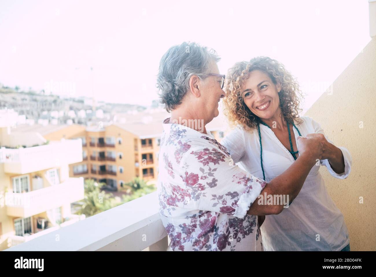 Two different ages women friends touch punch outdoor at home in the ...