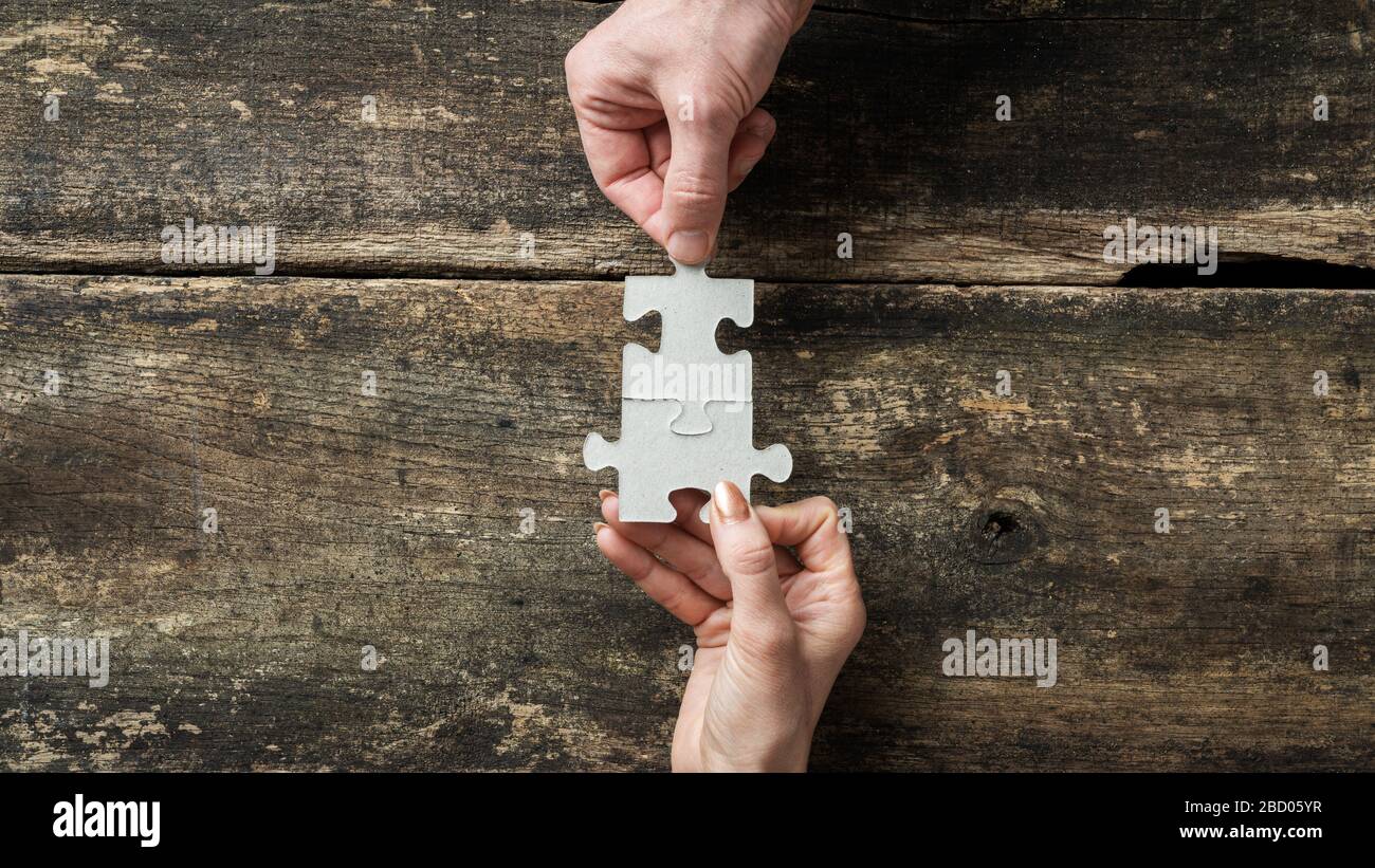 Top view of male and female hands joining two matching puzzle pieces ...