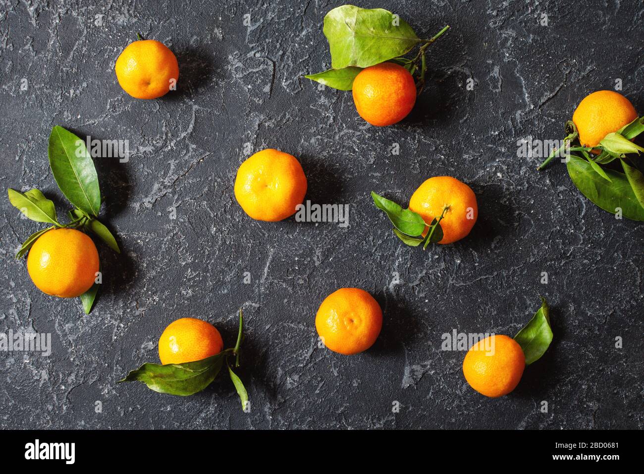 Fresh organic Tangerines with leaves on a black stone or concrete ...