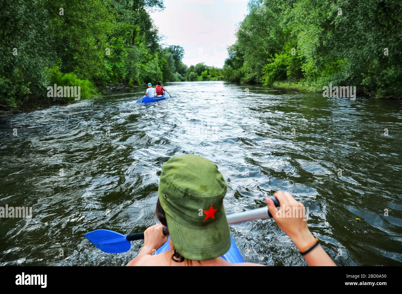 Girl floating in canoe on the river with friends during active summer ...
