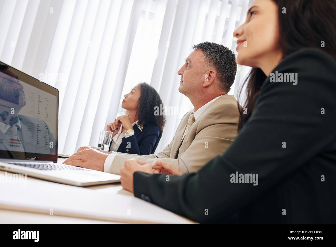 Group of multi-ethnic business team watching presentation of colleague ...