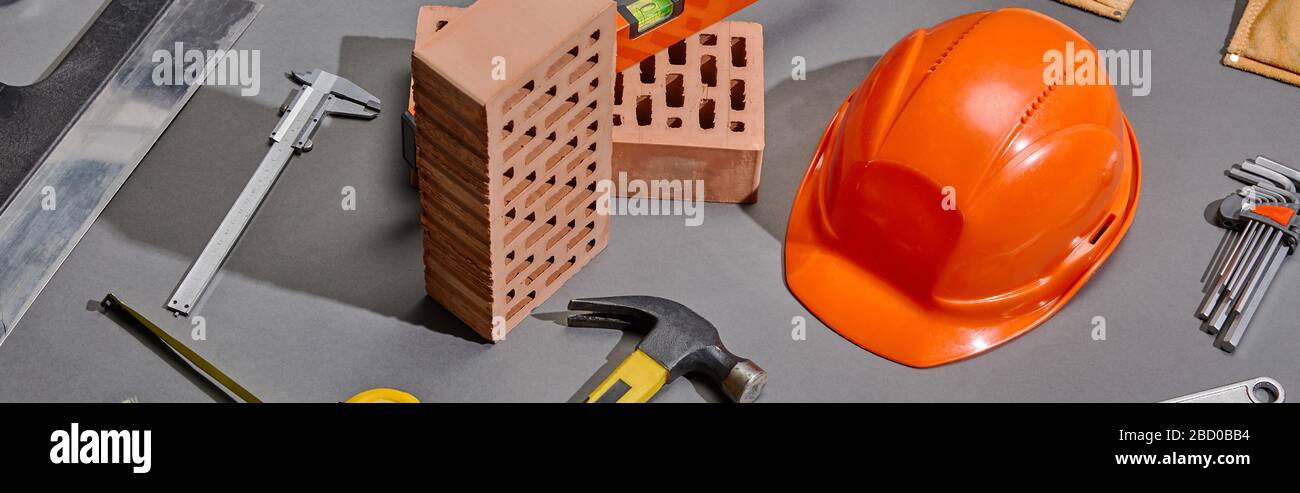 panoramic shot of bricks, hammer, angle keys, orange helmet, calipers ...