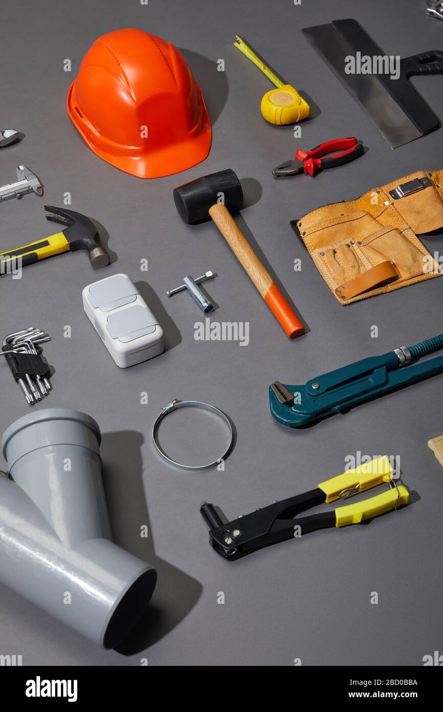 flat lay with helmet, tool belt and industrial tools on grey background ...