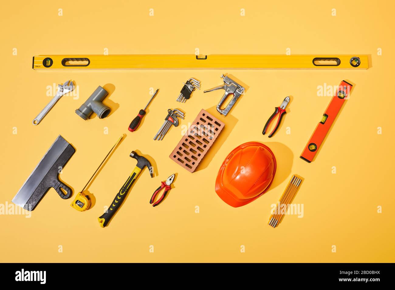 flat lay with industrial tools, brick and orange helmet on yellow ...