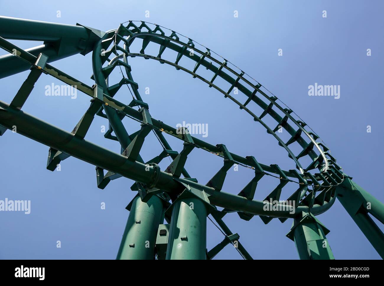 Curved Rollercoaster at a theme or amusement park empty green metal ...