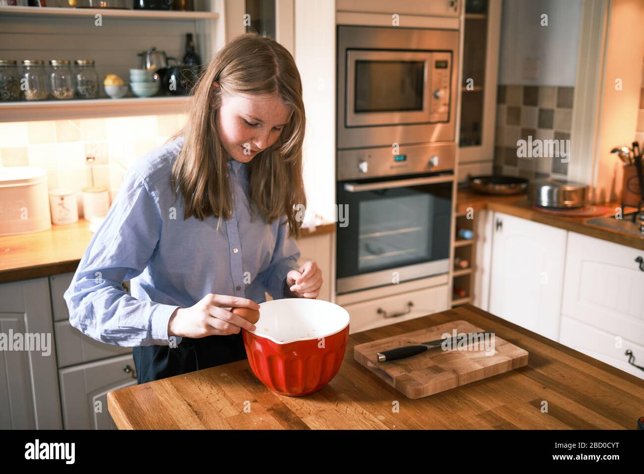 A teenage girl cooks at home in the kitchen breaking an egg into a bowl Stock Photo - Alamy