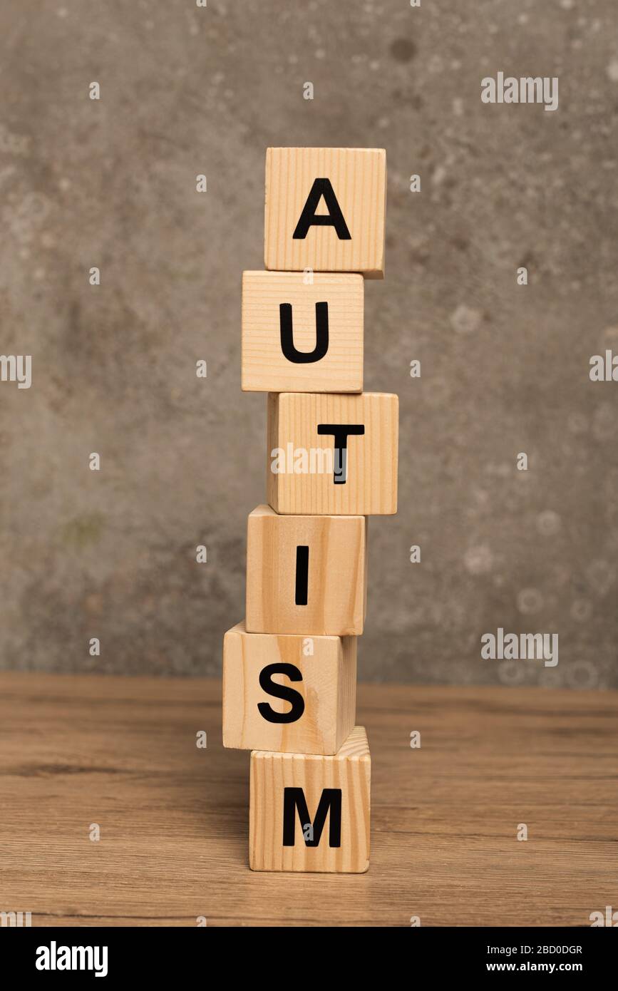 Stacked blocks with autism lettering on wooden table on textured grey ...