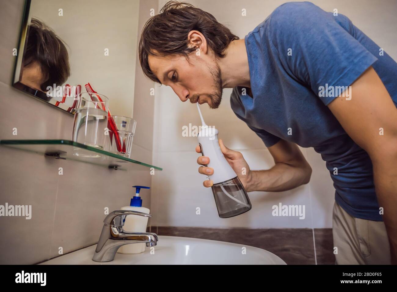 A man uses an oral irrigator in his bathroom Stock Photo - Alamy