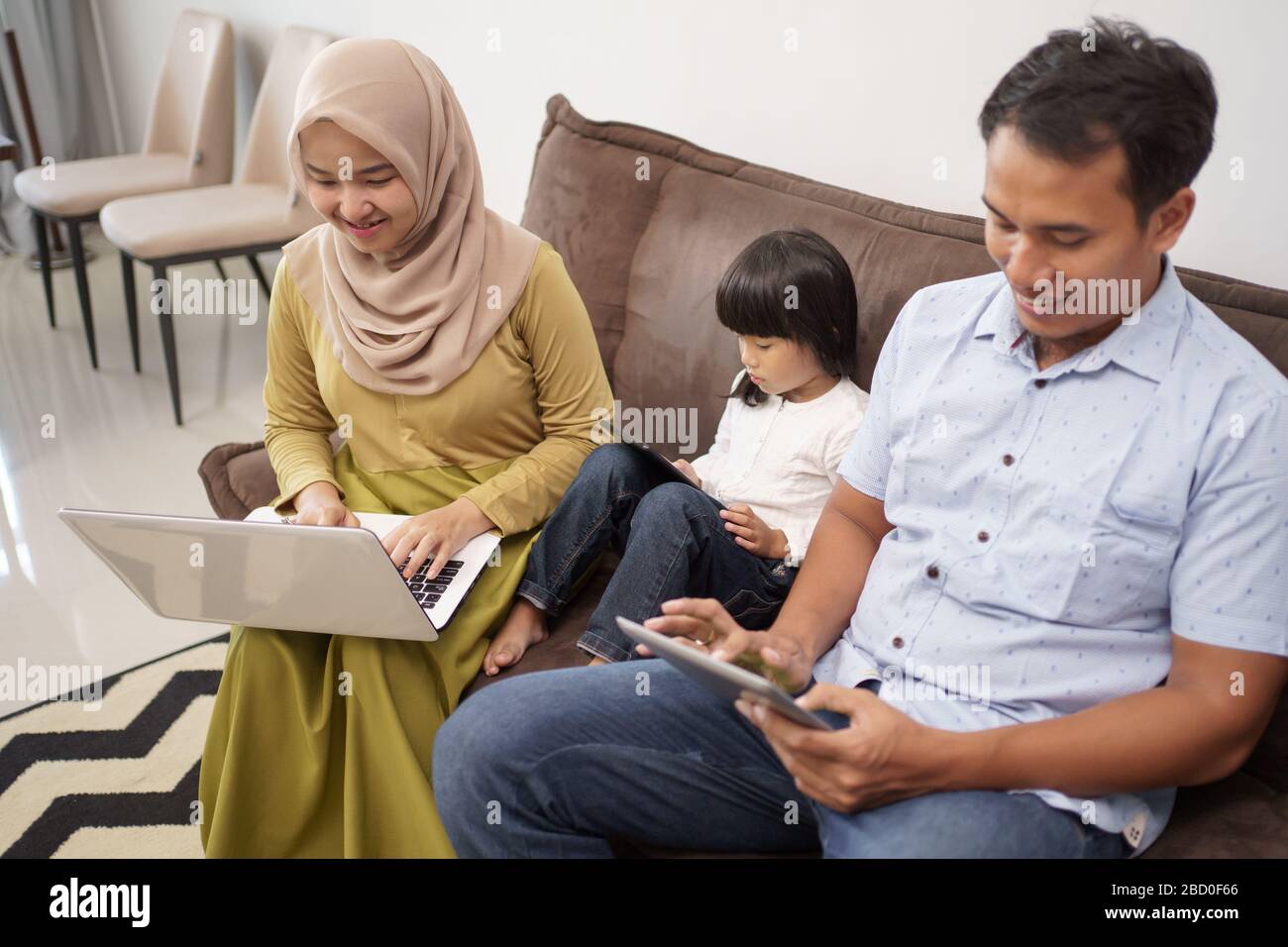 family working remotely from home sitting together using laptop and ...