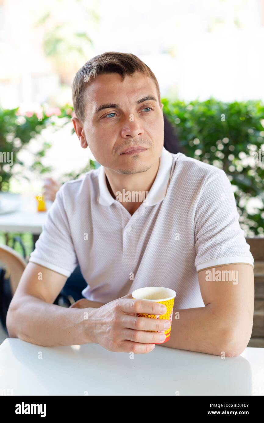 A 35-40 year old man is a lonely sad man sitting with a glass of coffee ...