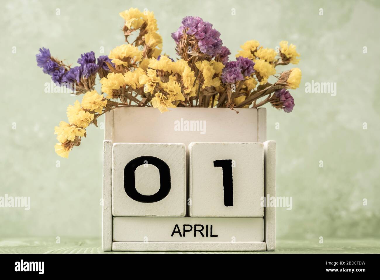 cube calendar for april decorated with flowers against green background ...