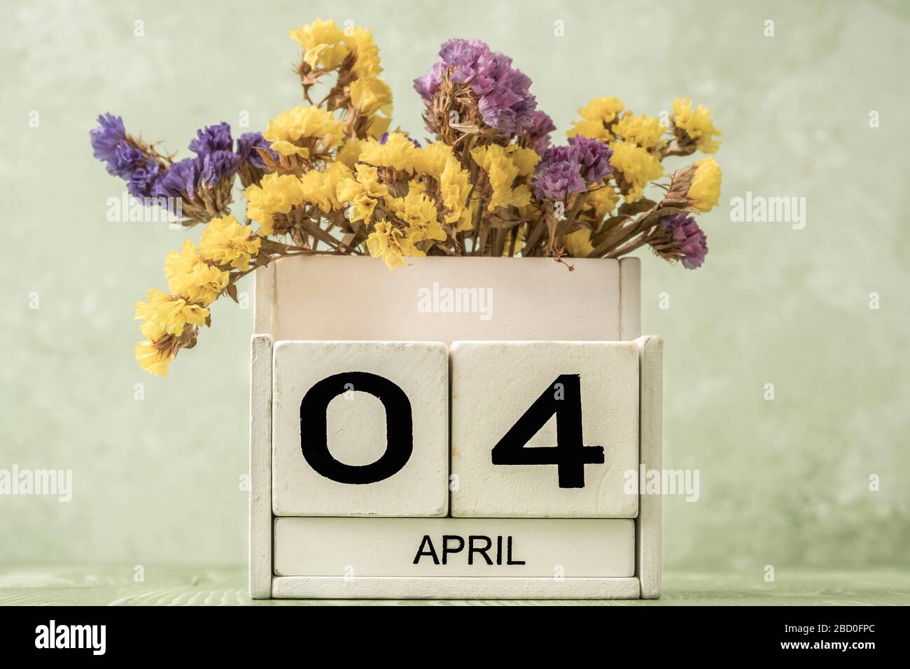 cube calendar for april decorated with flowers against green background ...