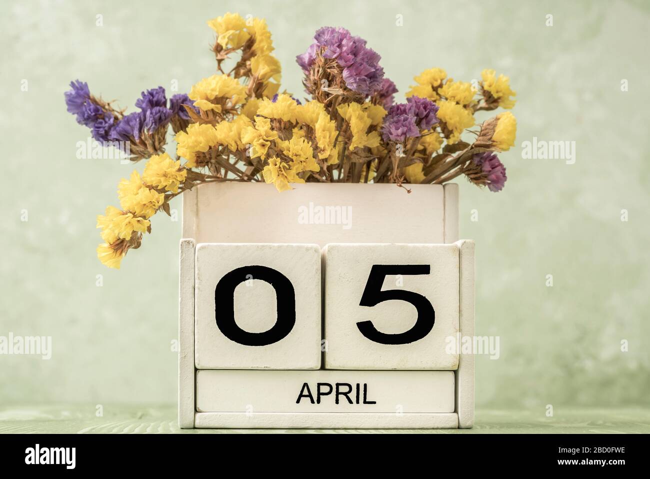 cube calendar for april decorated with flowers against green background ...