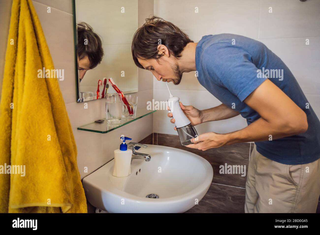 A man uses an oral irrigator in his bathroom Stock Photo - Alamy