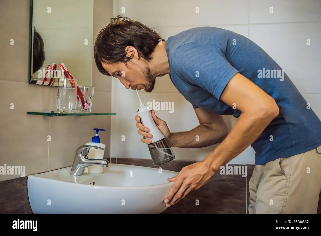 A man uses an oral irrigator in his bathroom Stock Photo - Alamy