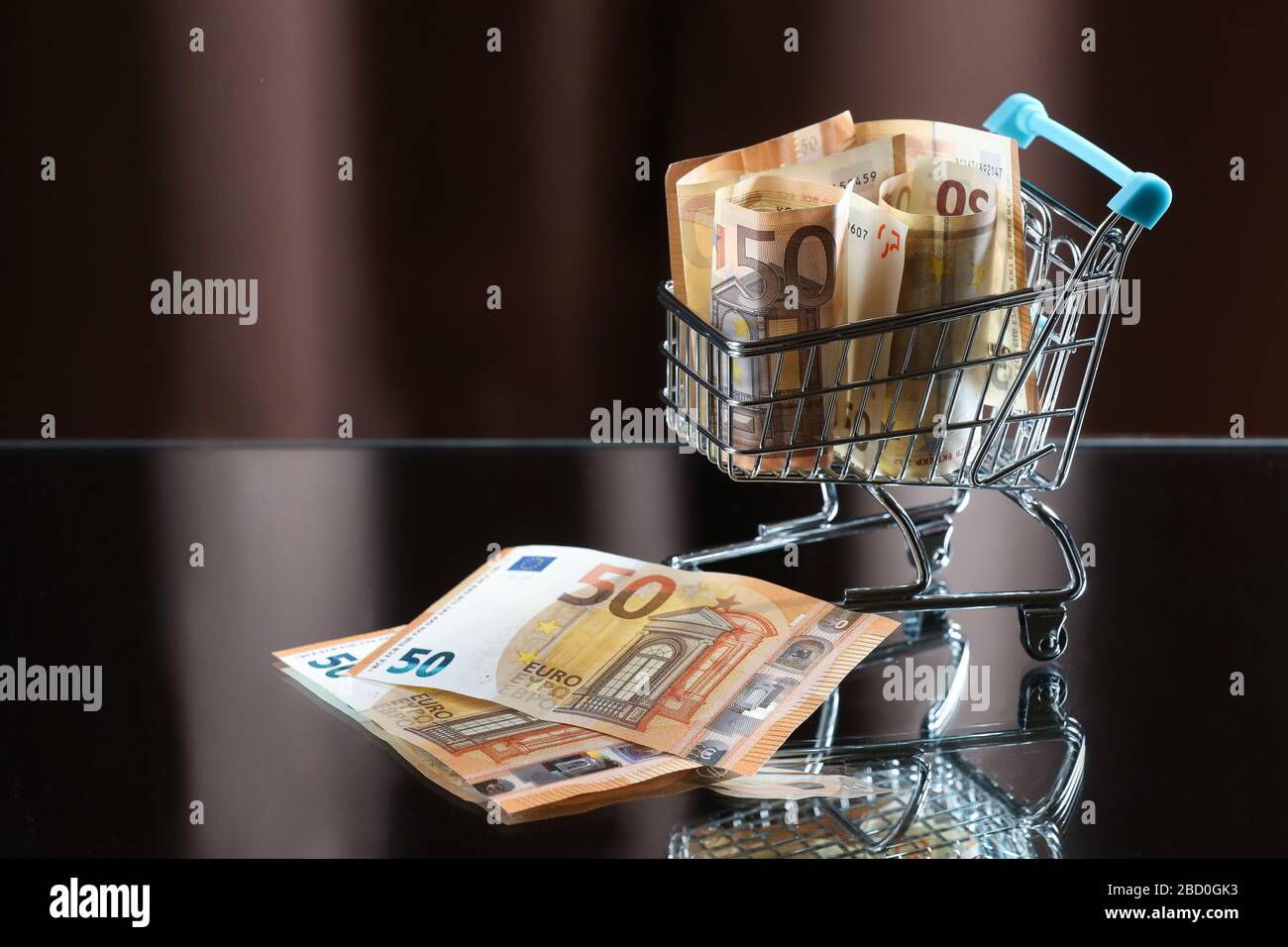 blue shopping cart with money. Reflected table. Dark background ...