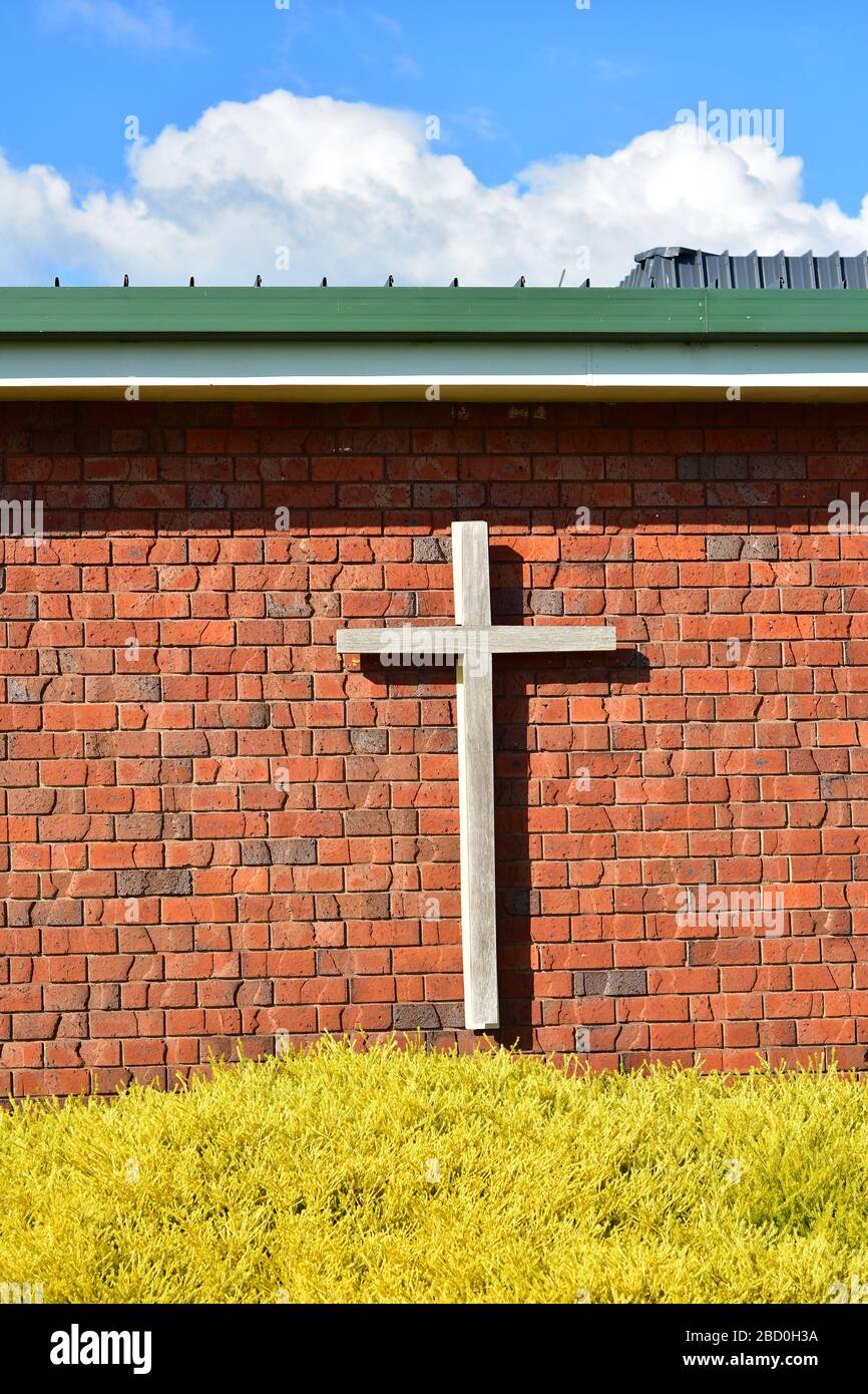 Wooden Christian cross on red brick exterior wall of contemporary ...