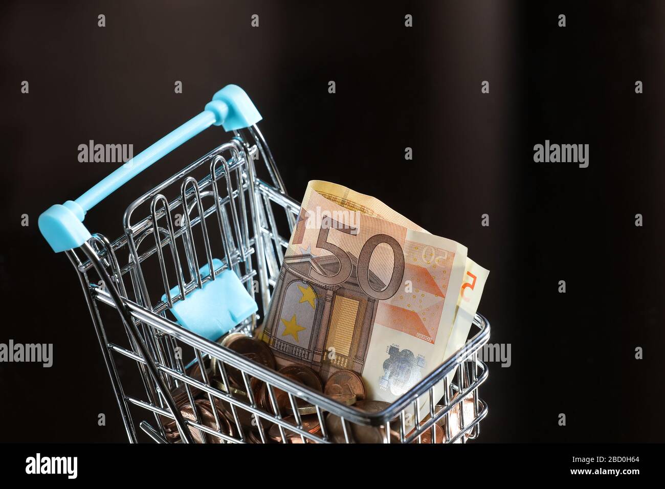 blue shopping cart with money. Reflected table. Dark background ...