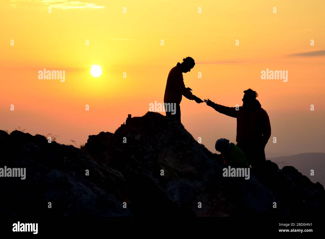 Two friends helping each other and with teamwork trying to reach the ...