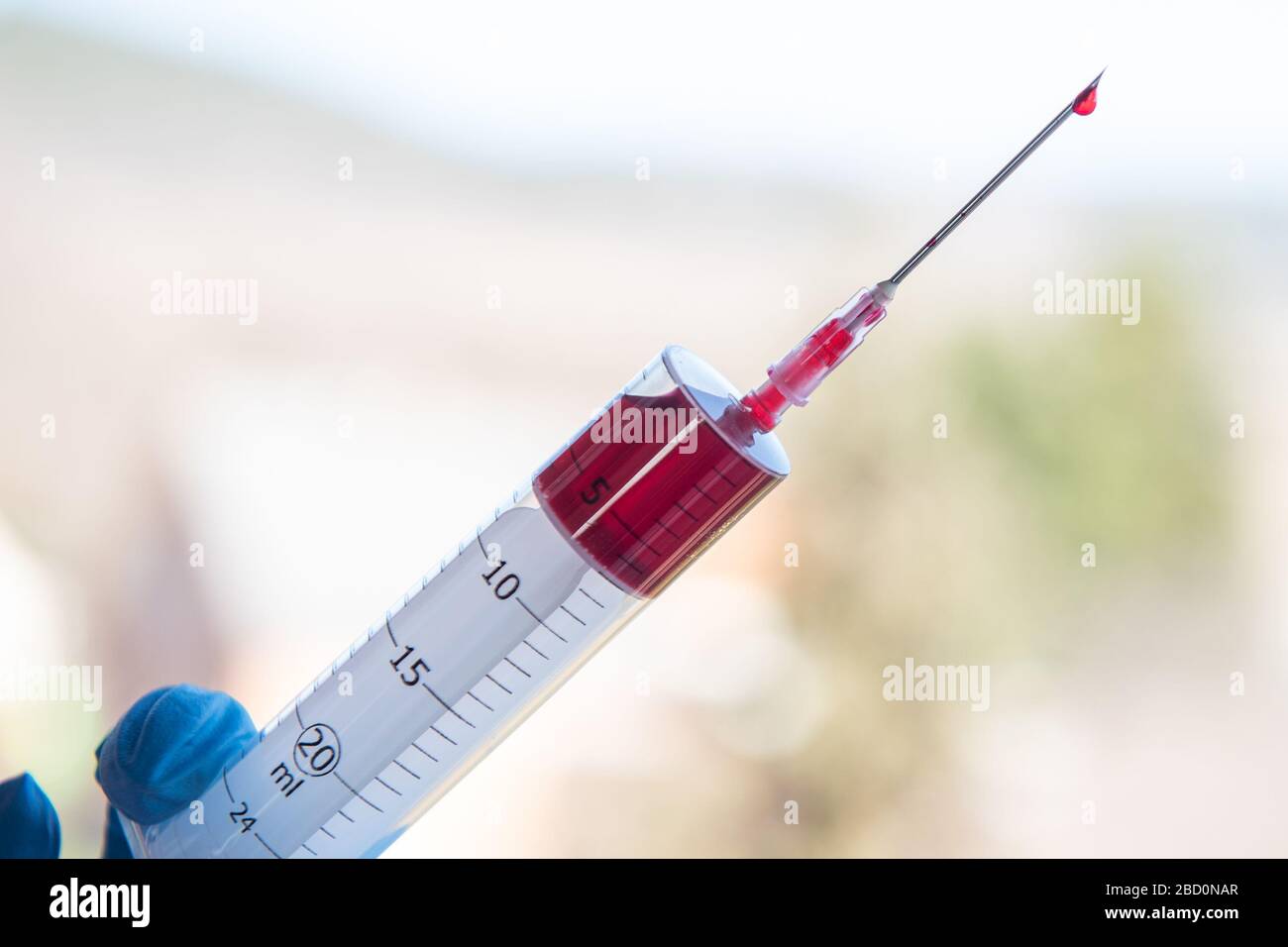 Injection syringe with blood with gloved hand Stock Photo - Alamy
