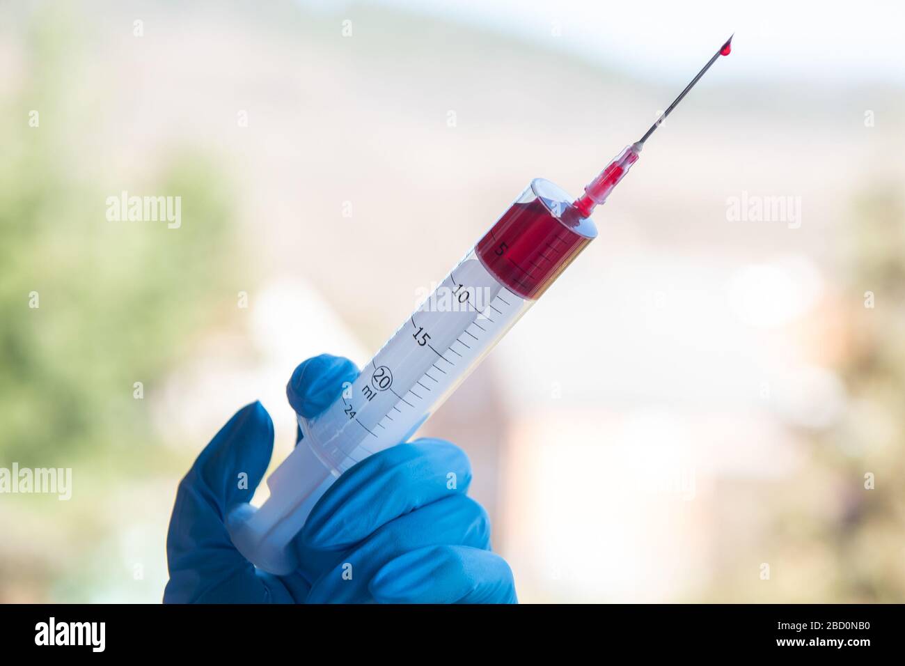 Injection syringe with blood with gloved hand Stock Photo - Alamy