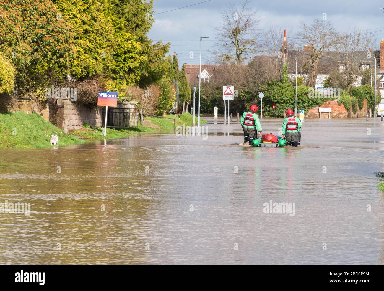 Emergency services carrying an iflatable boat through flood waters on ...