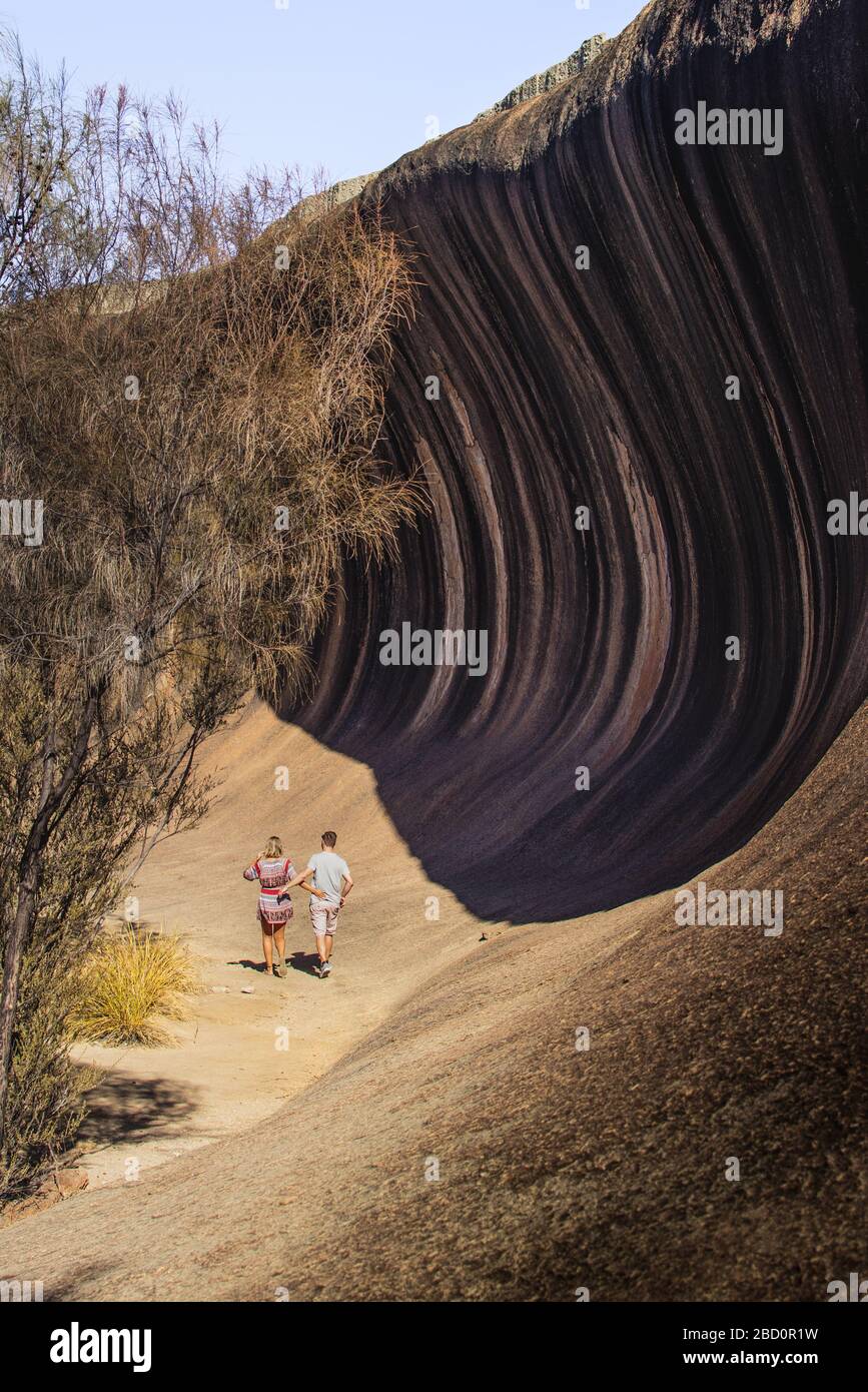A couple wandering in an unsual rock formation name wave rock in ...