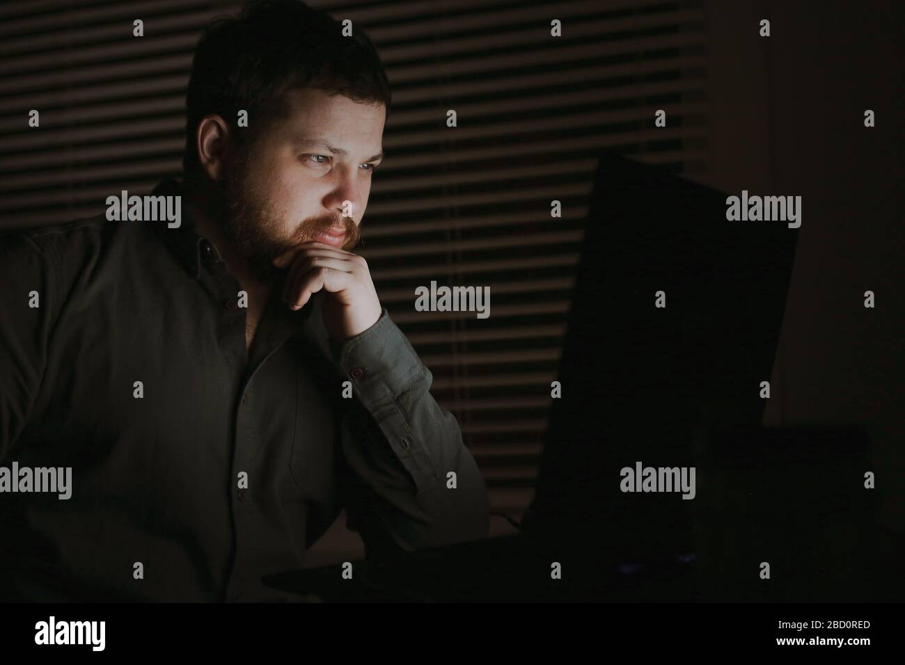 Thoughtful man reading article by laptop at nigth Stock Photo - Alamy