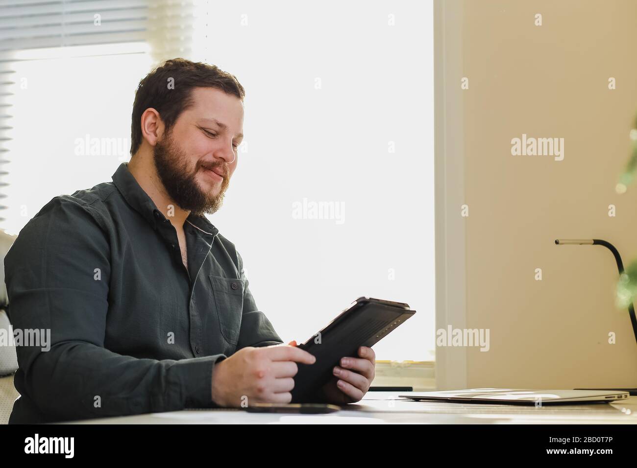 Male manager using tablet at office, laptop on desk Stock Photo - Alamy