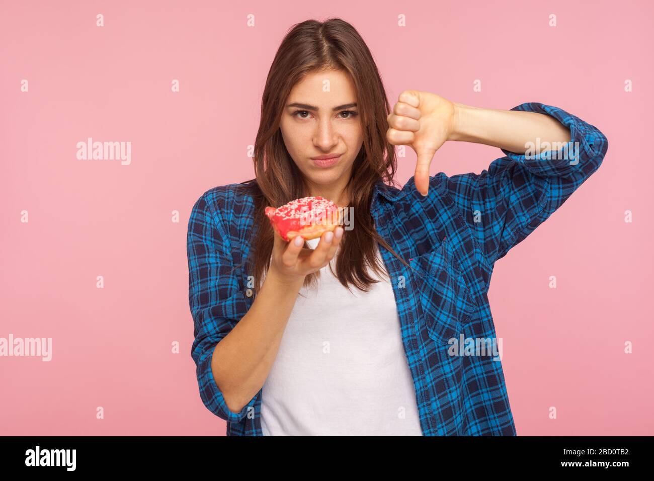 Portrait of girl disappointed in sugary junk food showing thumb down ...