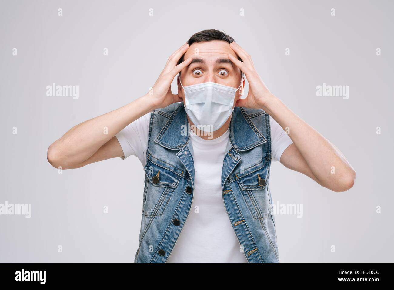 Scared man in medical mask afraid of something and looks into camera ...