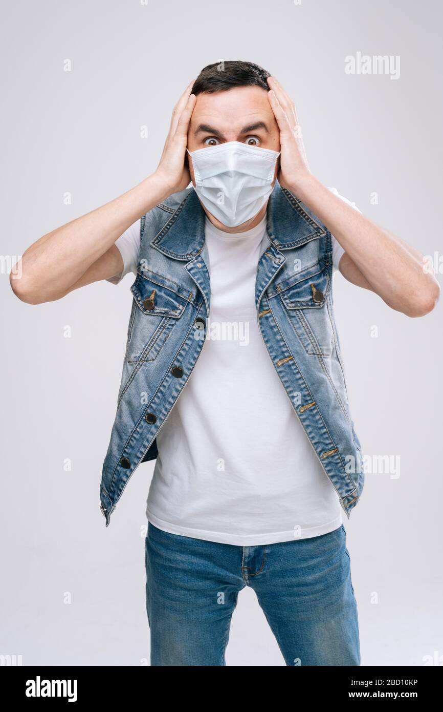 Scared man in medical mask afraid of something and looks into camera ...